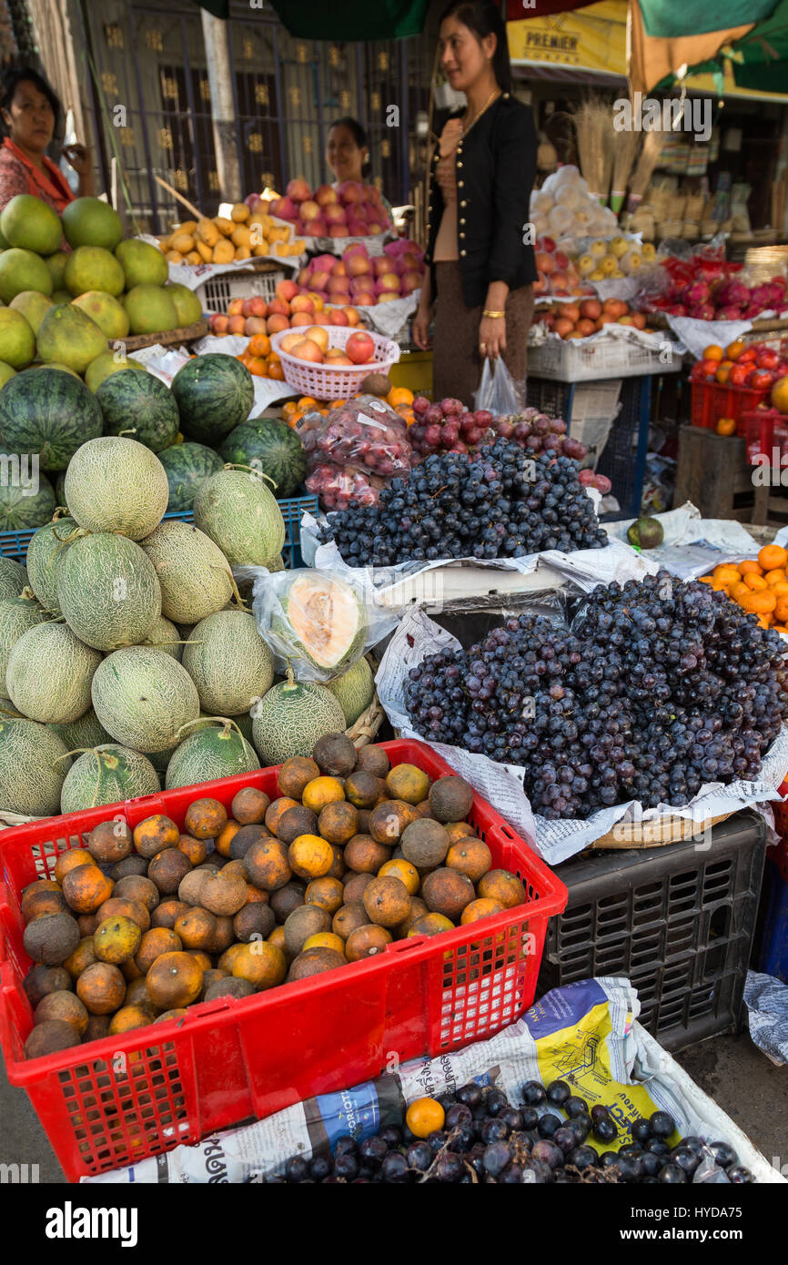 Heaps of different kinds of fruits in baskets and boxes and few people ...