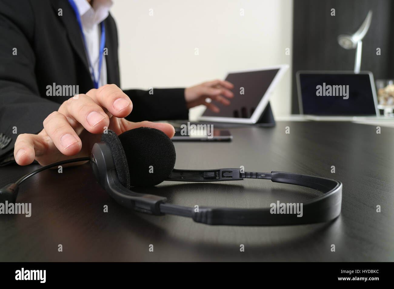 Man using VOIP headset with digital tablet and laptop computer as ...