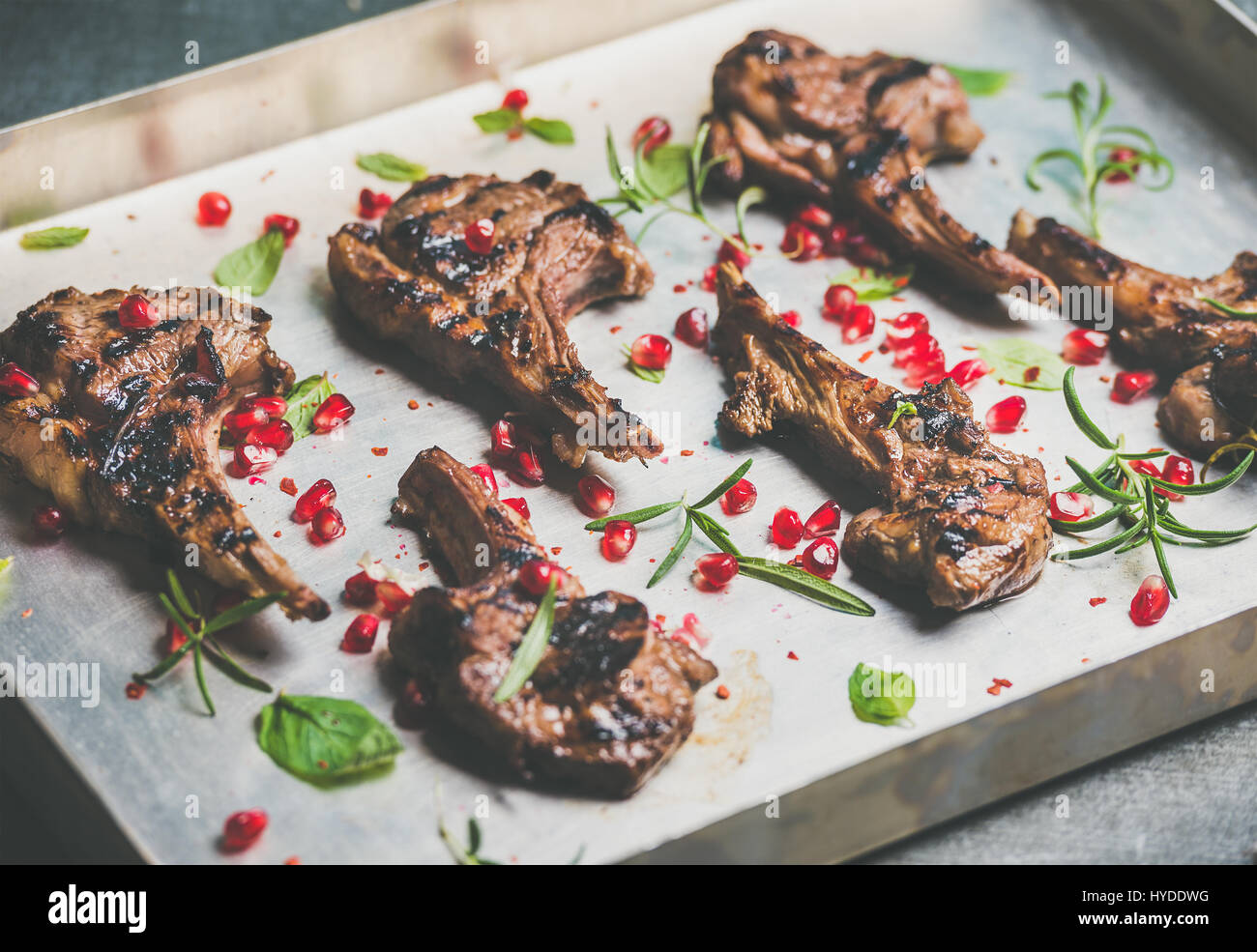 Grilled lamb ribs with pomegranate seeds and herbs in tray Stock Photo ...