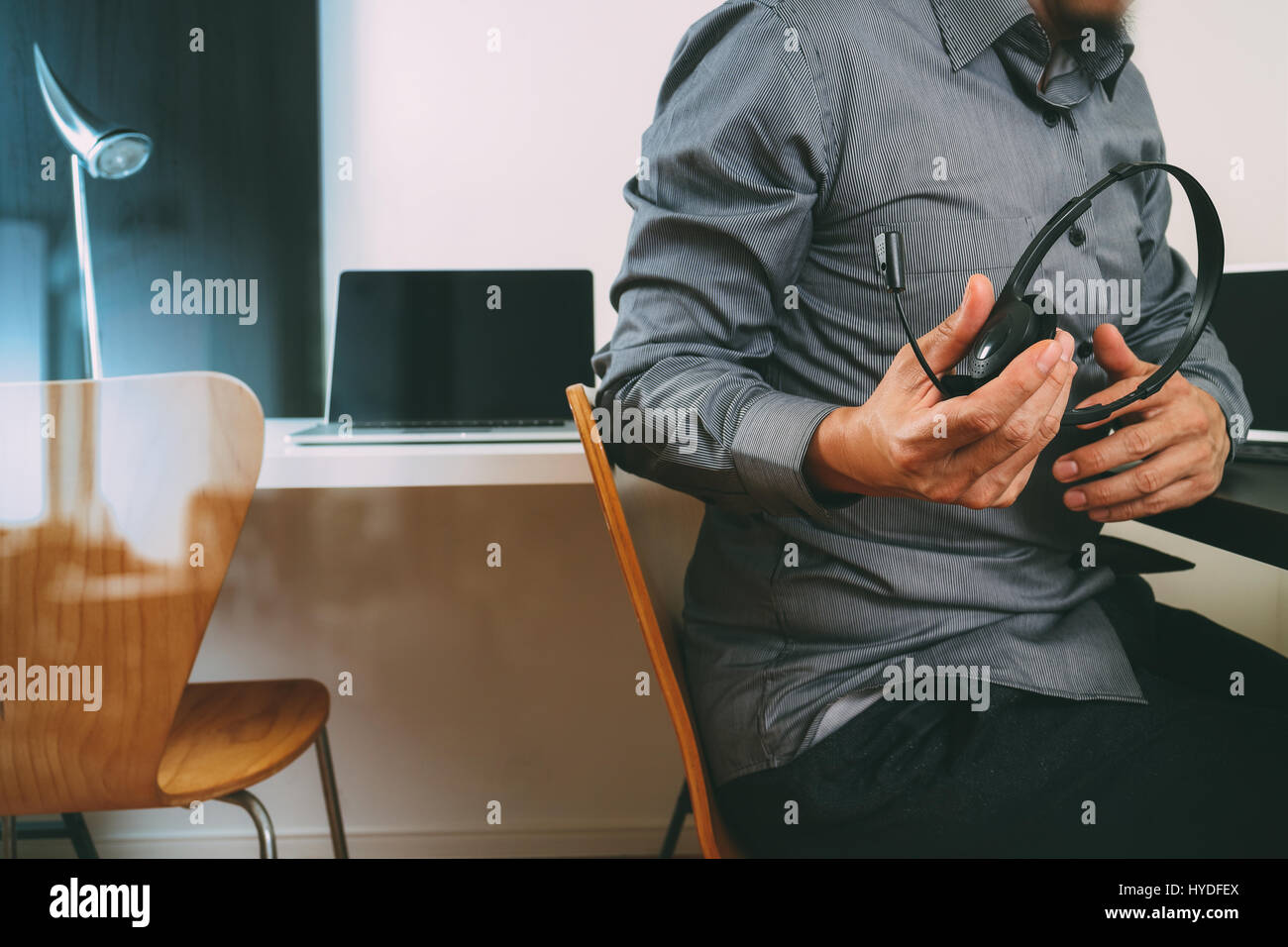 Man using VOIP headset with digital tablet and laptop computer as ...