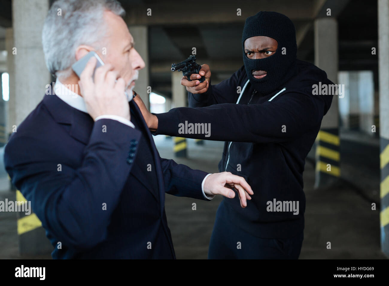 Serious rich businessman being robbed Stock Photo - Alamy
