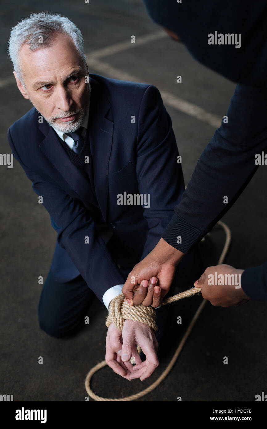 Sad cheerless man looking at his kidnapper Stock Photo - Alamy