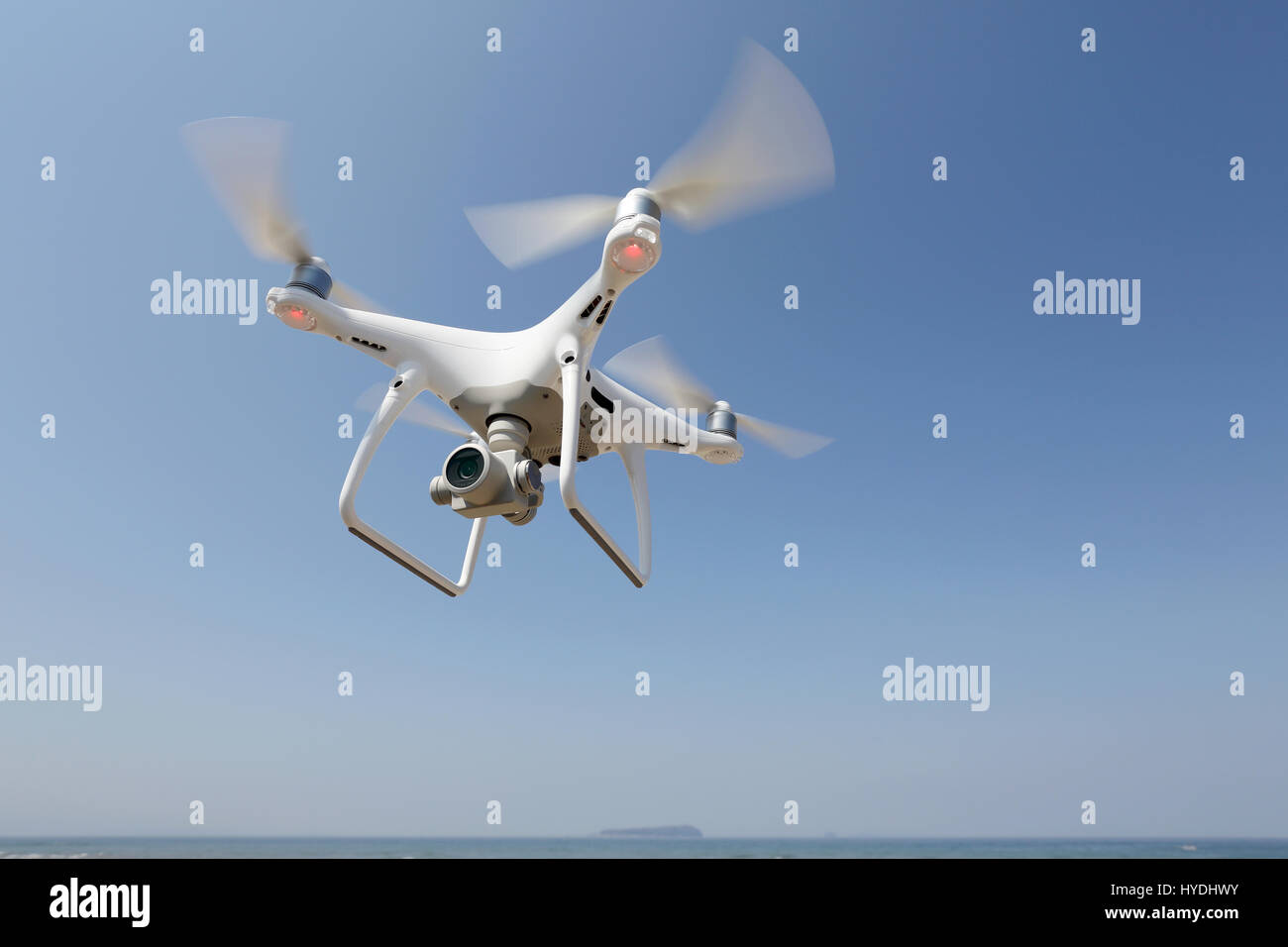 White drone quad copter with flying in the blue sky Stock Photo - Alamy