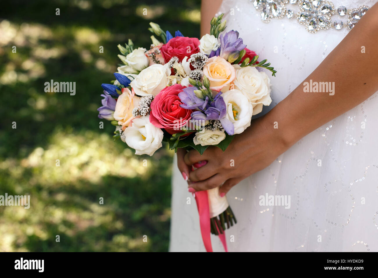 multicolor bouquet with pinlk ribbonin hands of the bride Stock Photo ...