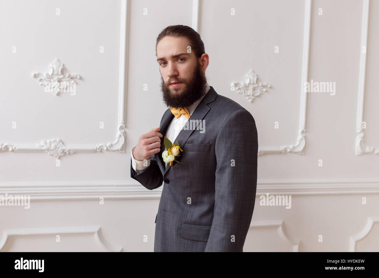 Handsome strong, brutal bearded groom posing in suit with orange bow on ...