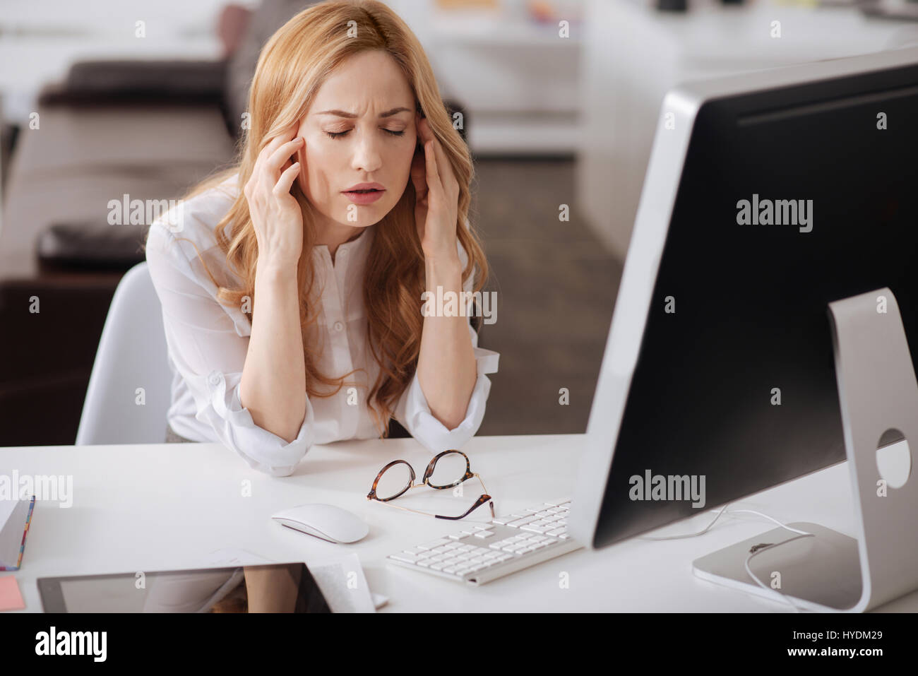 Depressed young office manager suffering from headache at workplace ...
