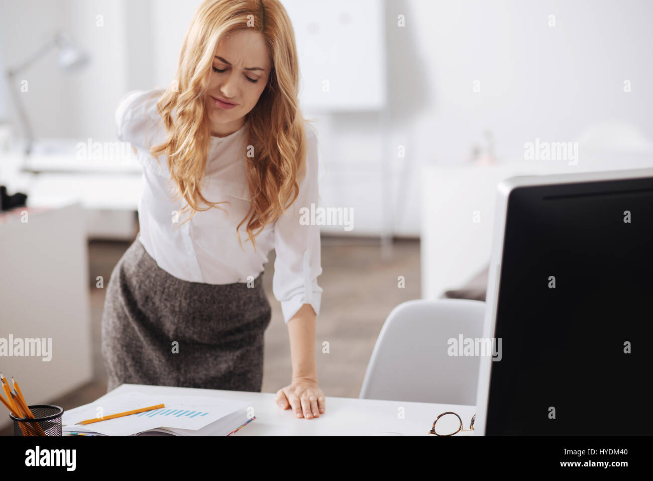 Distracted young woman feeling pain in her back in the office Stock ...