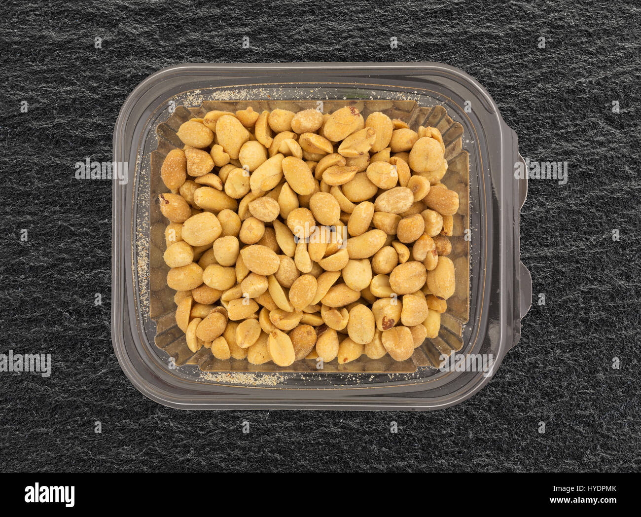 Top view of a container of barbecue flavored peanuts on a black slate ...