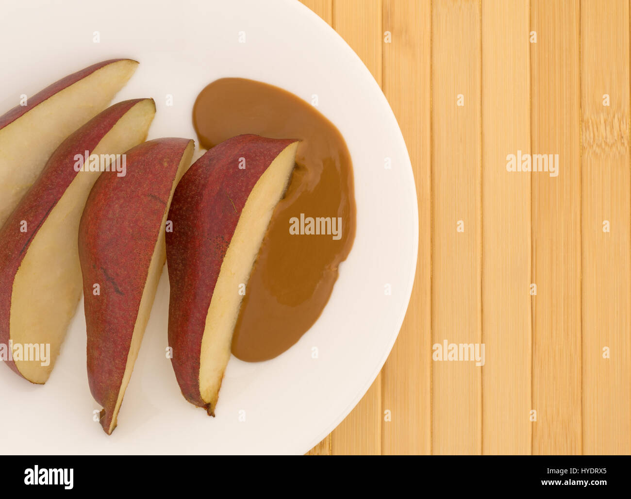 Top view of slices of a red pear on a plate with peanut butter atop a ...