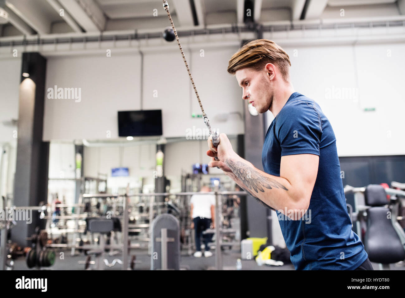 Fit young man in gym working out on pull-down machine Stock Photo - Alamy