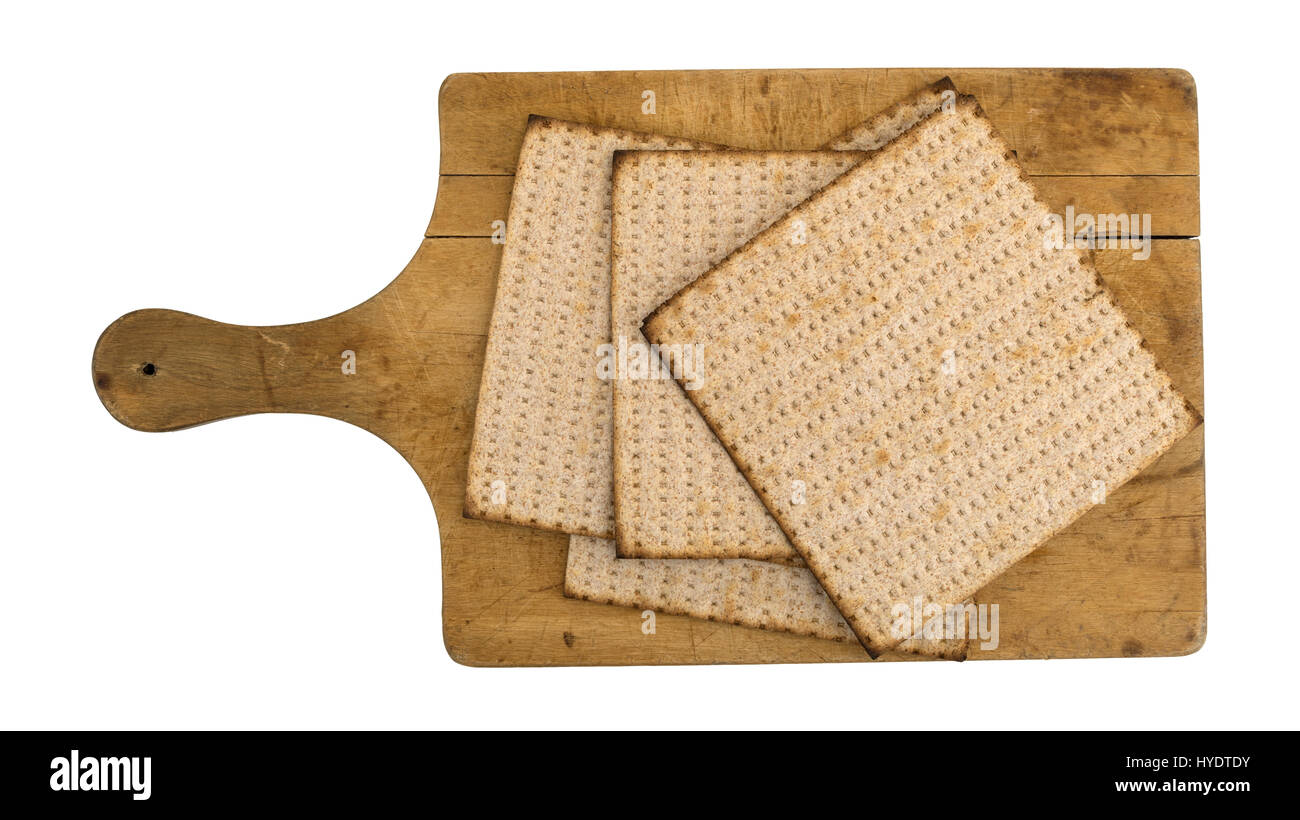 Top view of several whole wheat matzo crackers atop an old wood cutting ...