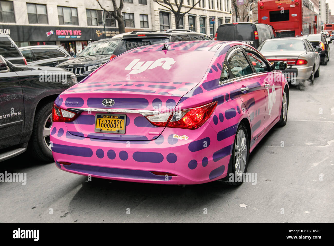 A pink car with Lyft logo is driving along 14th street in Manhattan ...