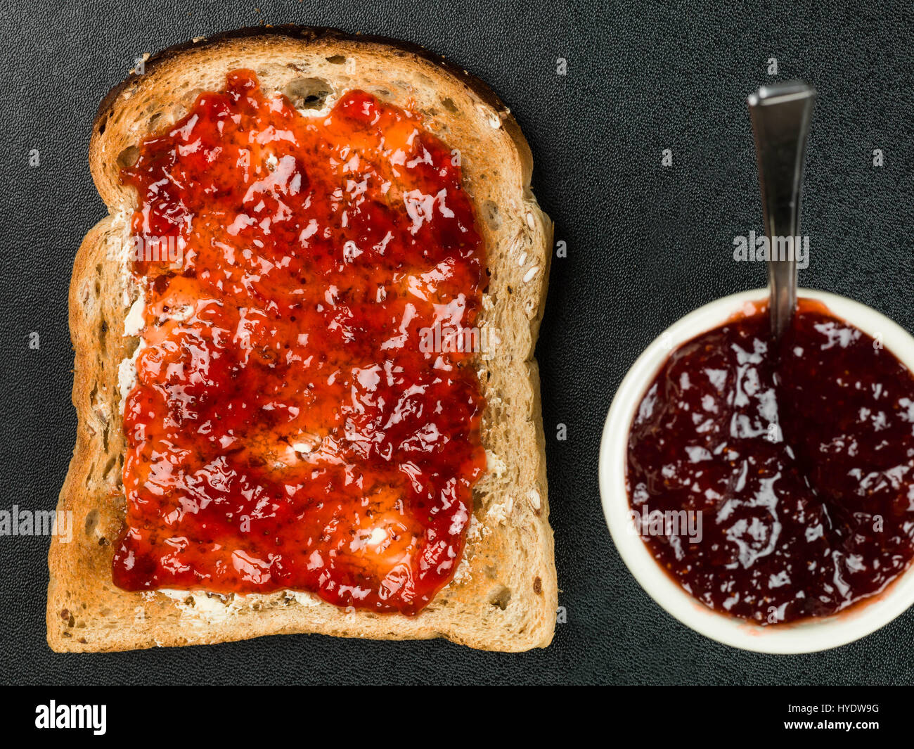 Strawberry Jam or Preserve on Buttered Toast Against a Black Background ...
