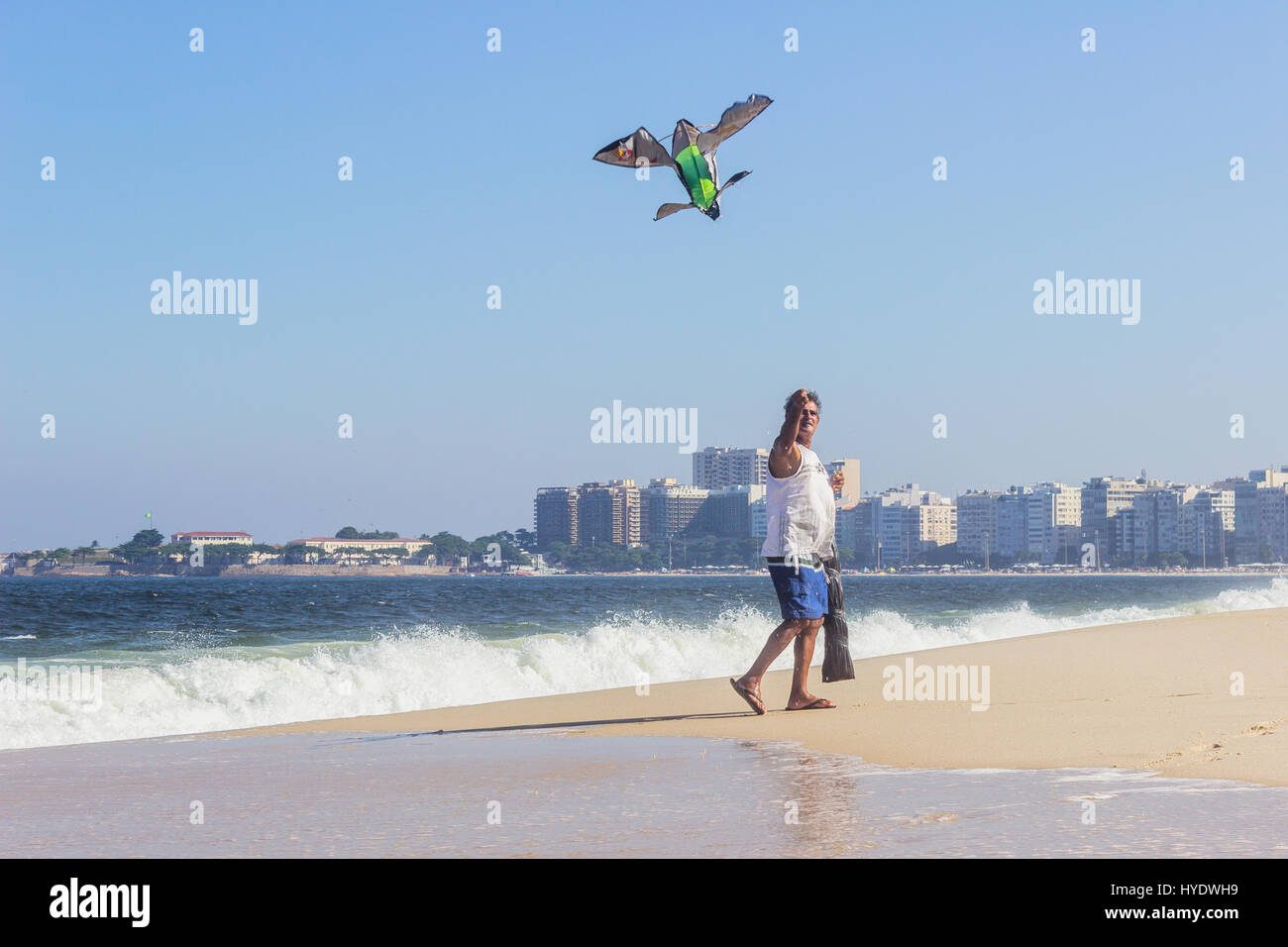 Brazil, Rio de Janeiro: Man flying a bird shaped kite on Copacabana ...