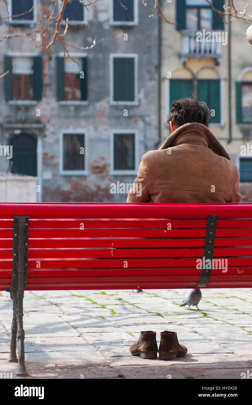 A man on a bench without shoes in Venice, Italy Stock Photo - Alamy