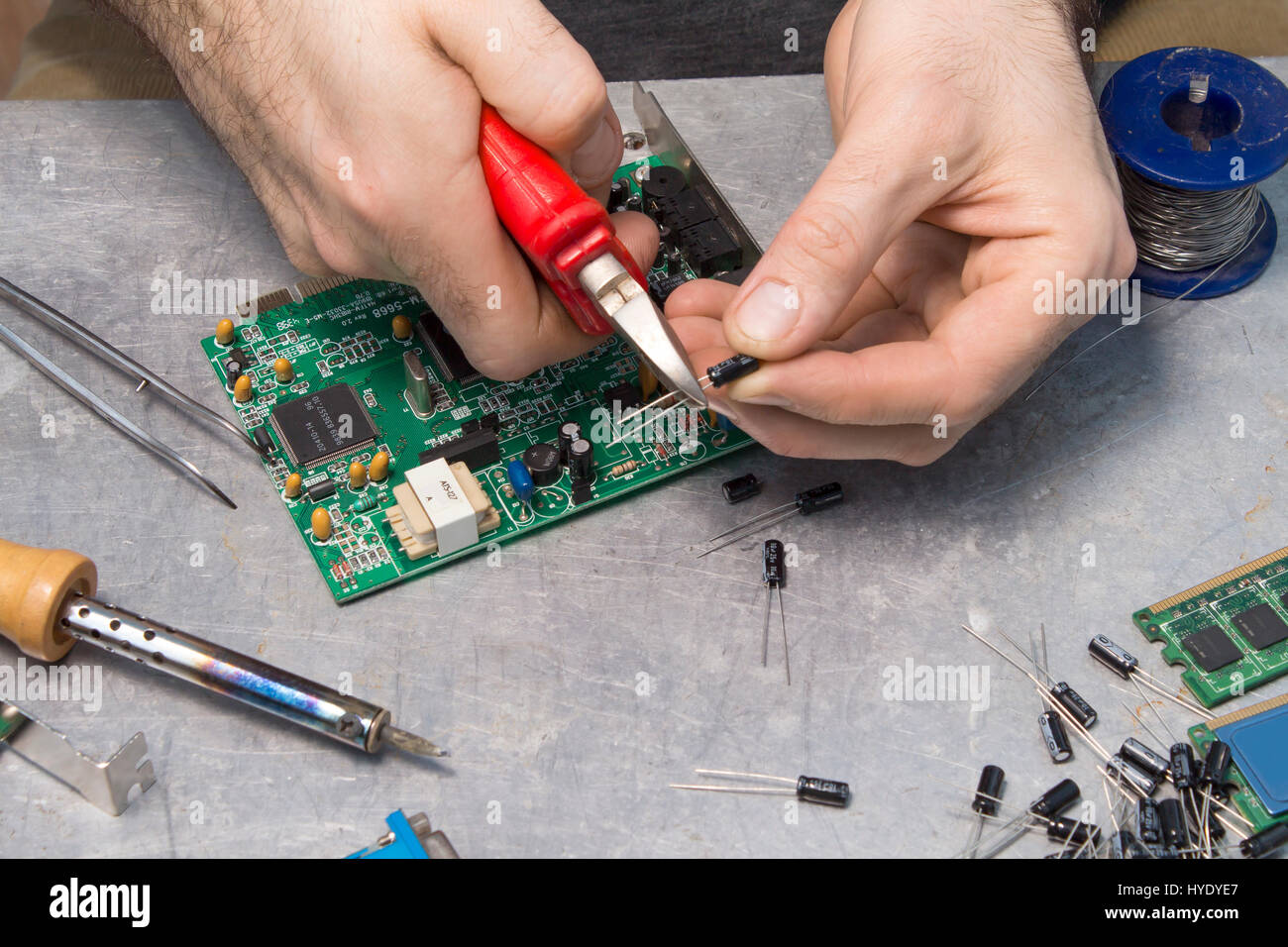 An electronic service worker cuts the tip of the capacitor with a ...