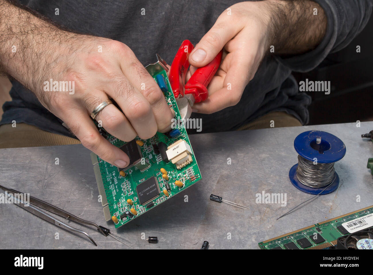 An electronic service worker cuts the tip of the capacitor with a ...