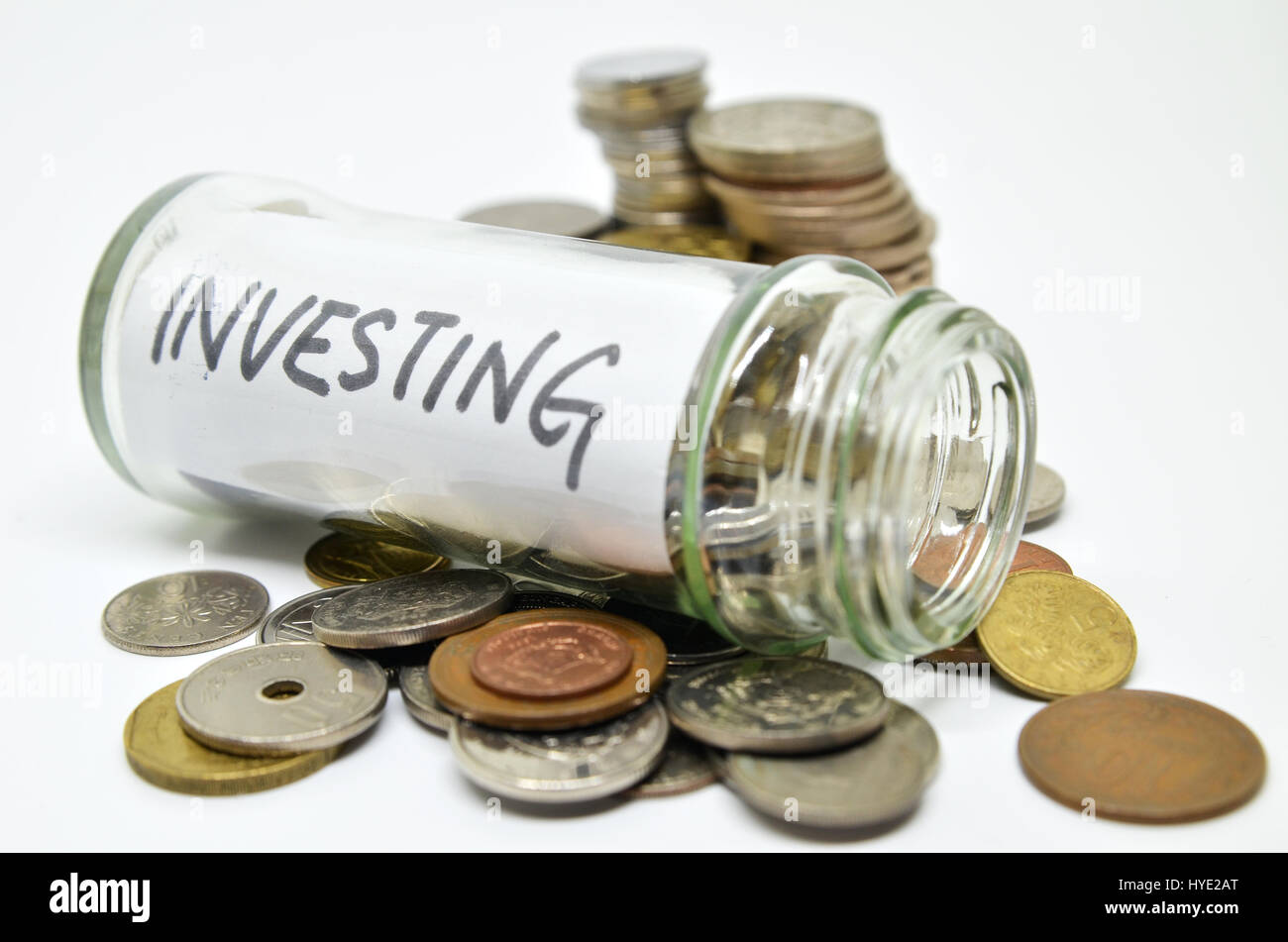 Investment lable in a glass jar with coins spilling out isolated on ...
