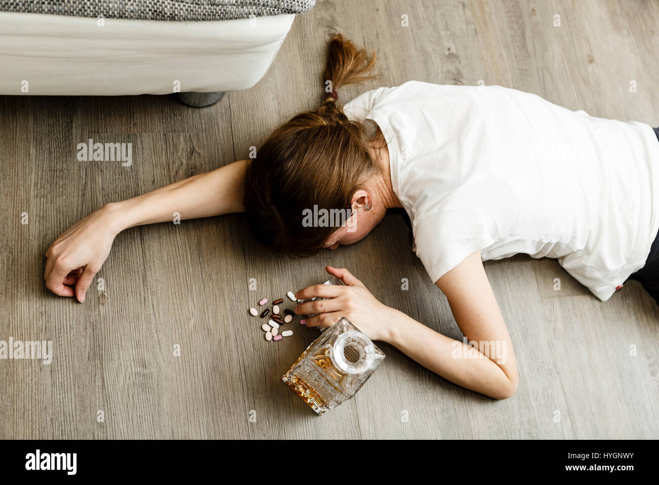 drunk or poisoned young woman with bottle of alcohol and pills, whisky ...