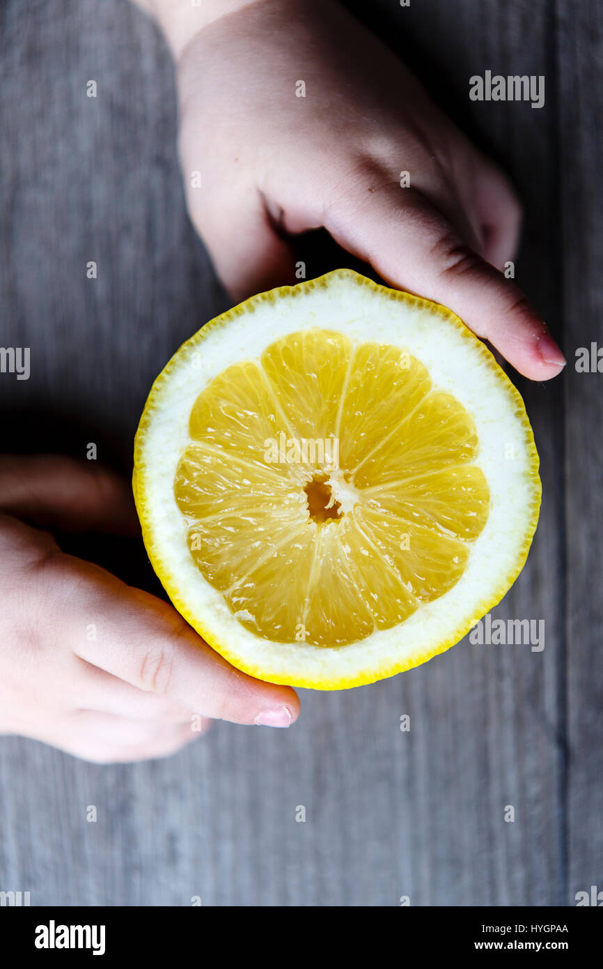 beautiful fresh yellow lemon in little cute kid hands and fingers on ...