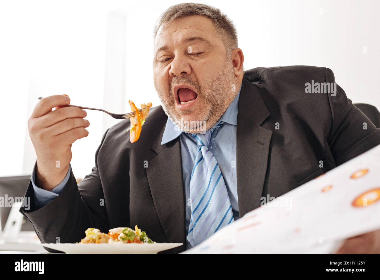 Hardworking tireless employee working a eating at the same time Stock ...