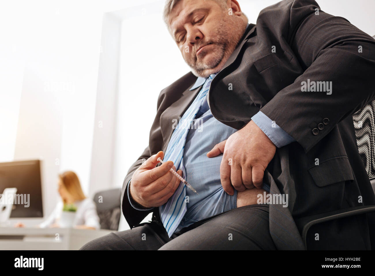 Corpulent office worker giving himself daily injection Stock Photo - Alamy