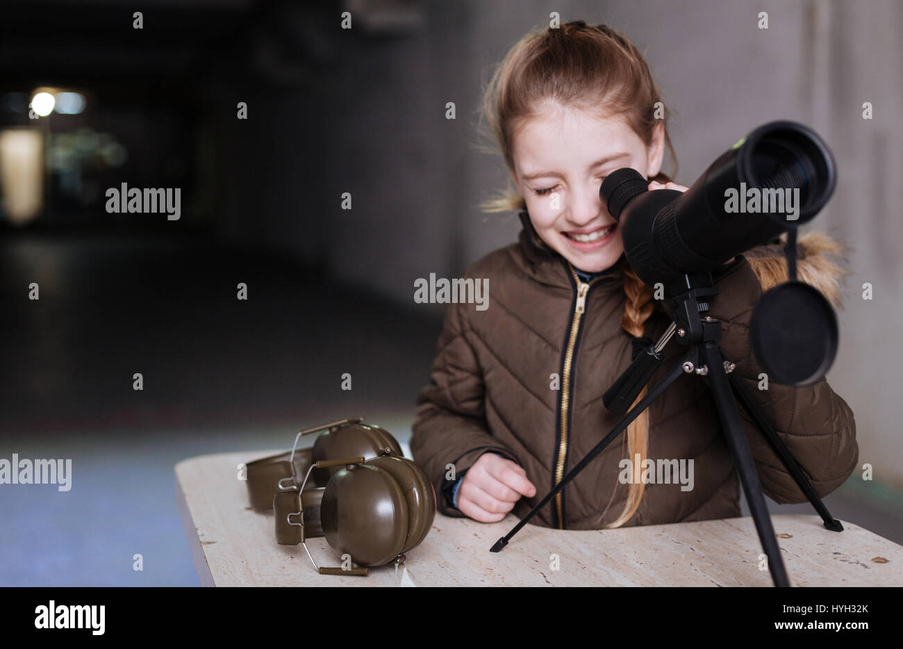 Positive cheerful girl looking into the telescope Stock Photo - Alamy