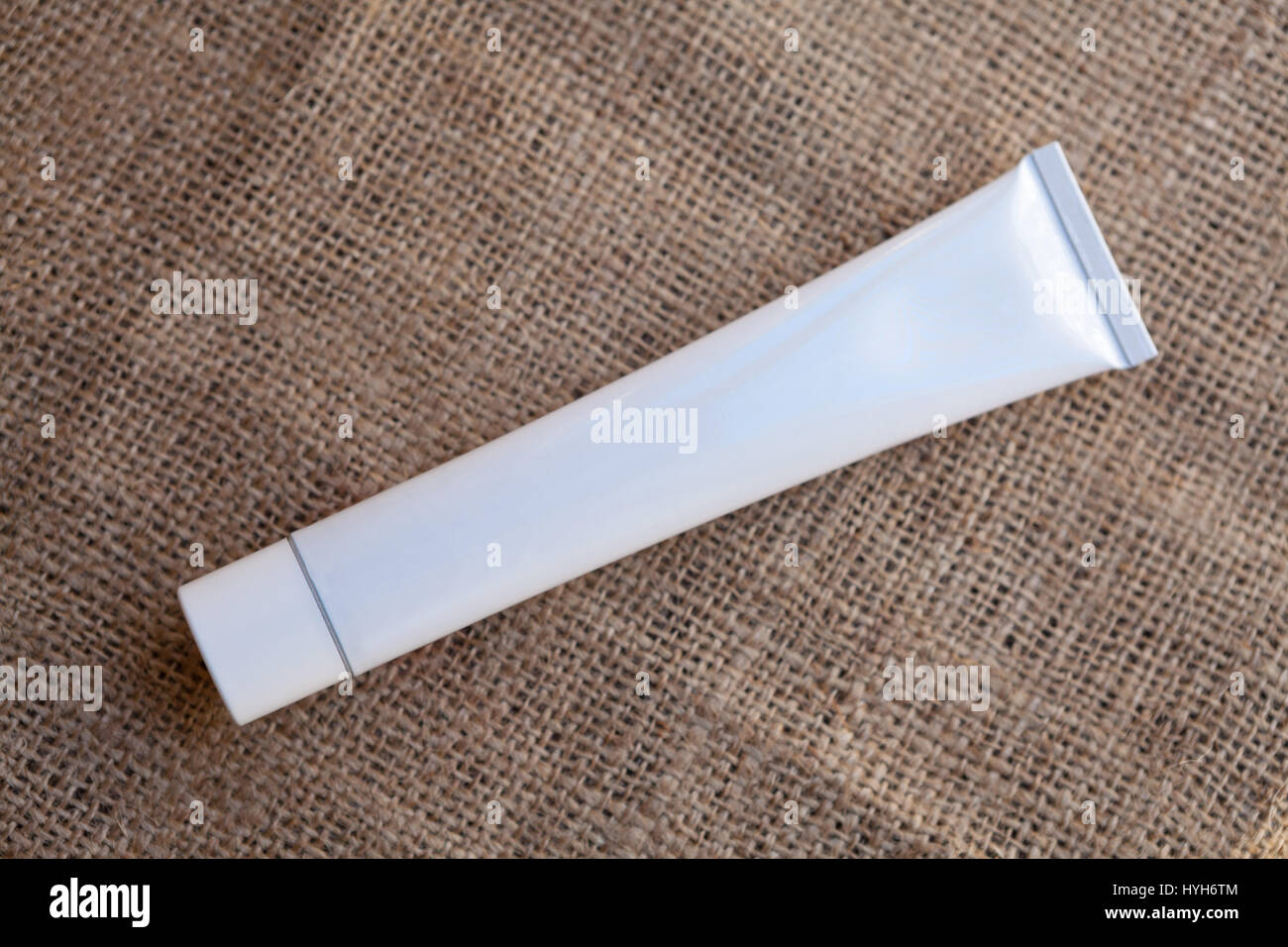 White, empty and clean tube, ready for your design product, on hessian ...