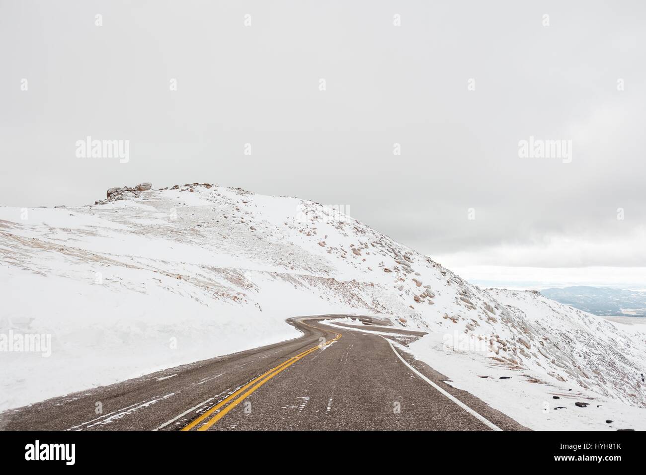 Winding road in between snow hills on an overcast day in Colorado Stock ...
