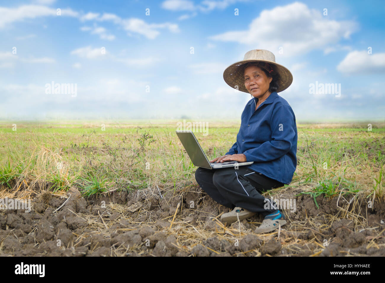 Asian Thai farmer using laptop computer in the rice field smile with ...