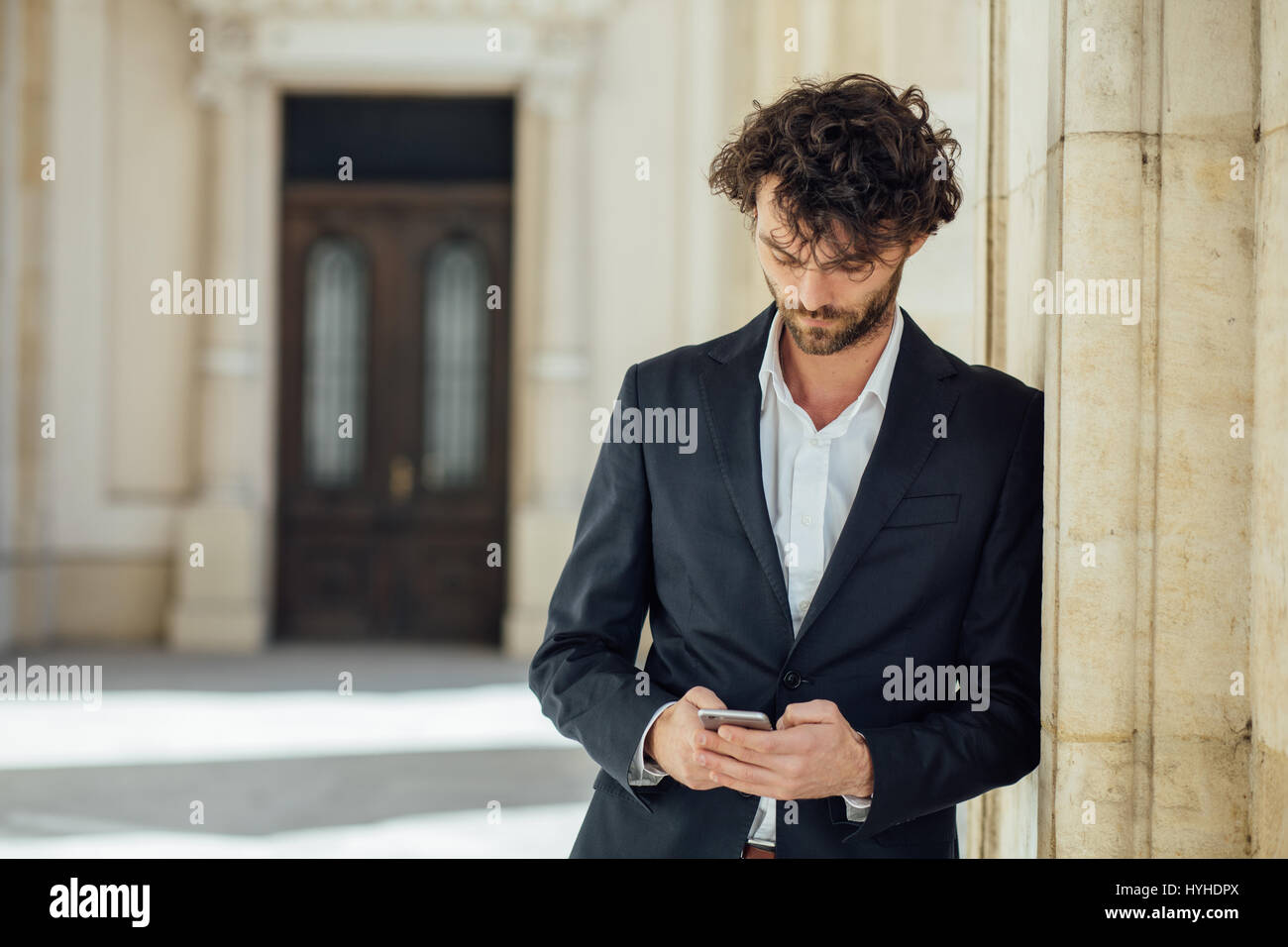 elegant handsome man standing next to columns of an old big building ...