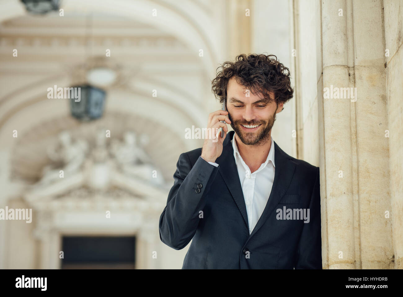 elegant handsome man standing next to columns of an old big building ...