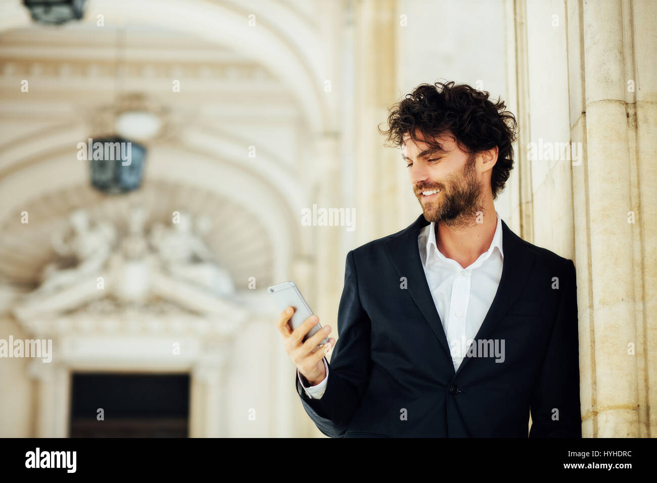 elegant handsome man standing next to columns of an old big building ...