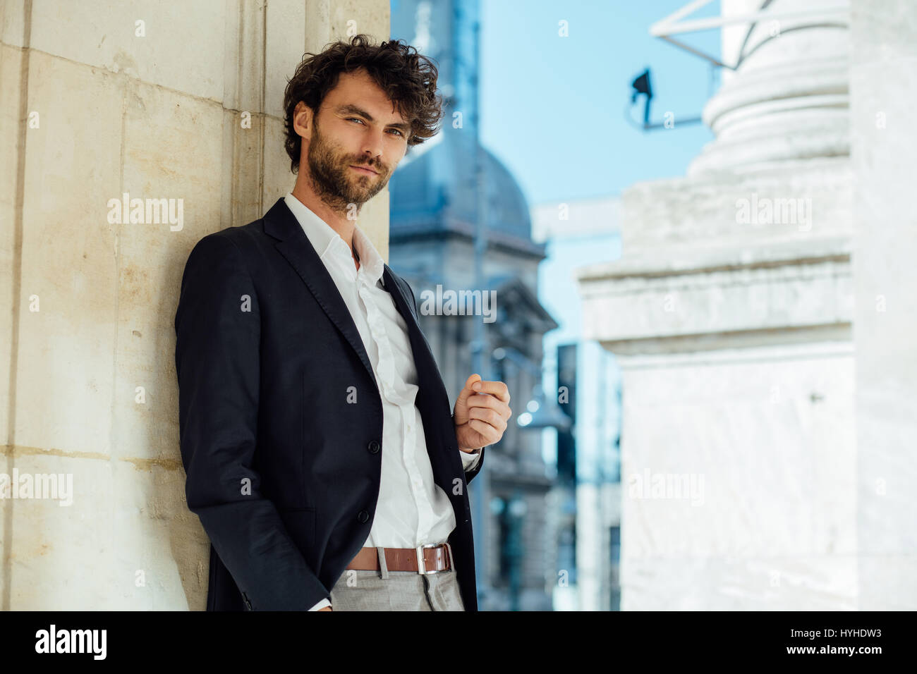 elegant handsome man standing next to columns of an old big building ...
