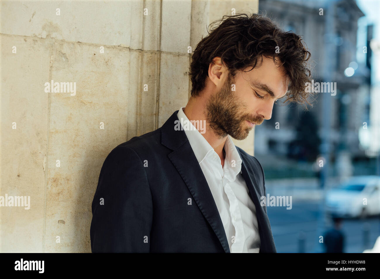elegant handsome man standing next to columns of an old big building ...