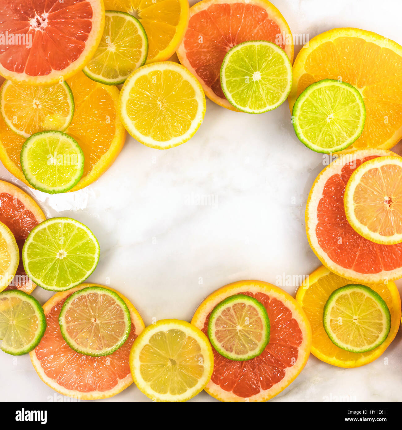 A vibrant frame made up of juicy citrus fruits, on a white marble ...