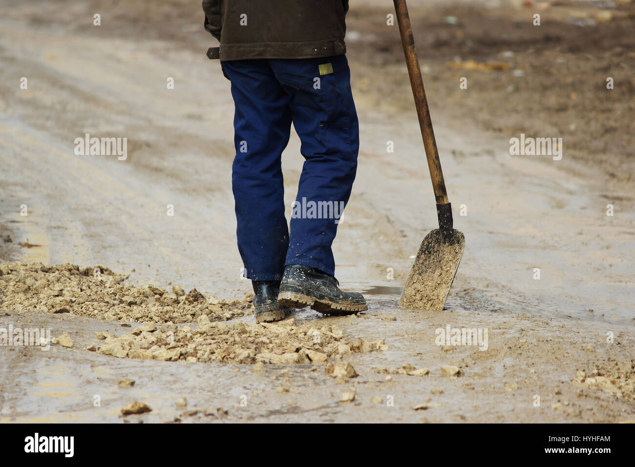 A worker with a shovel strews gravel in pits to level the road Stock ...