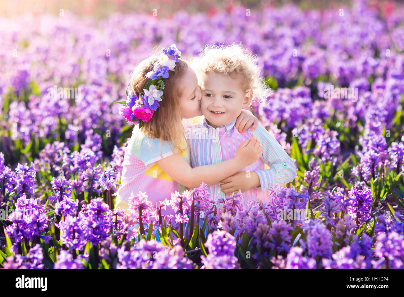 Kids gardening. Children play outdoors in hyacinths meadow. Little girl ...