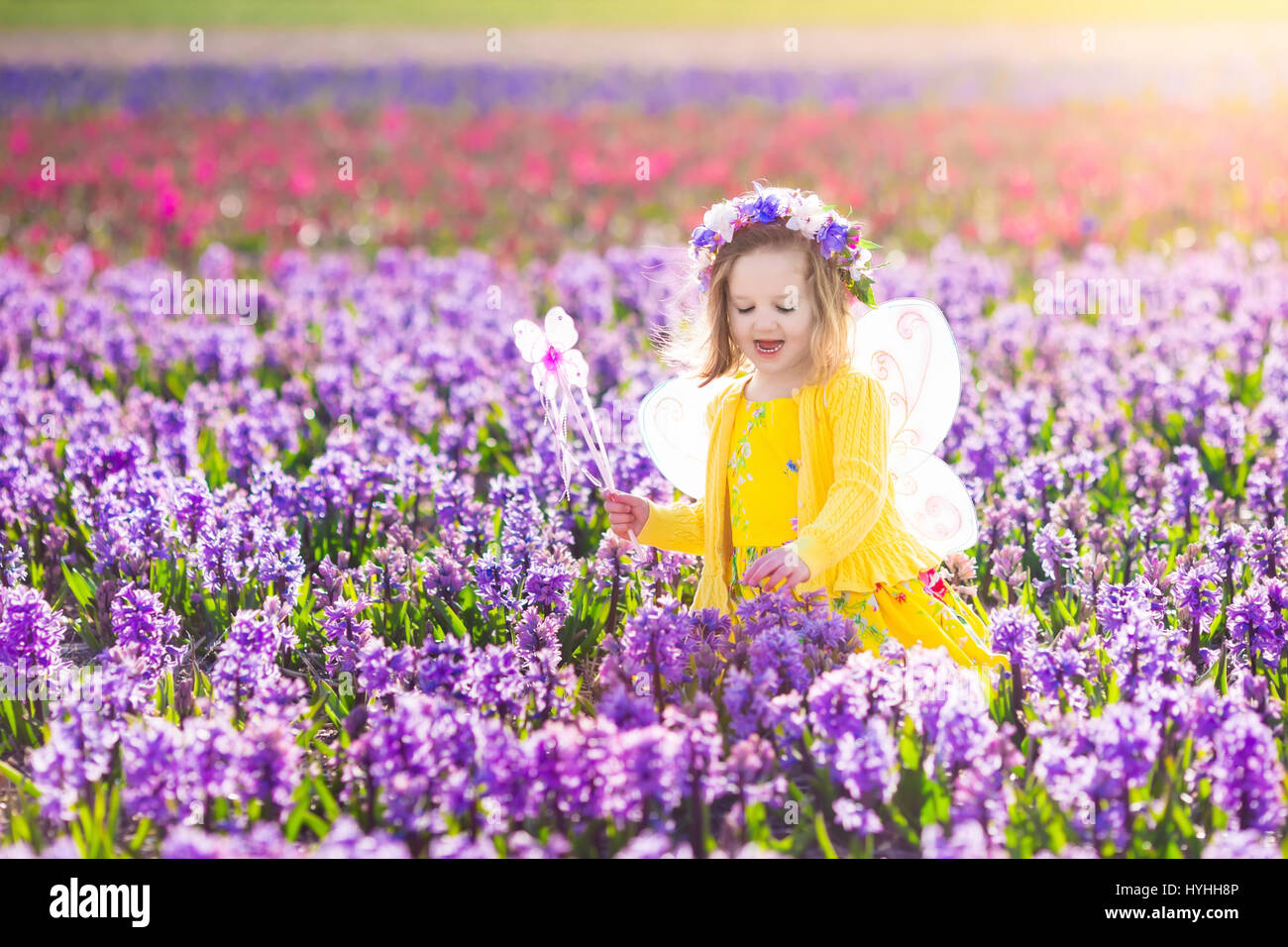 Beautiful girl playing in blooming hyacinth flower field. Kids princess ...