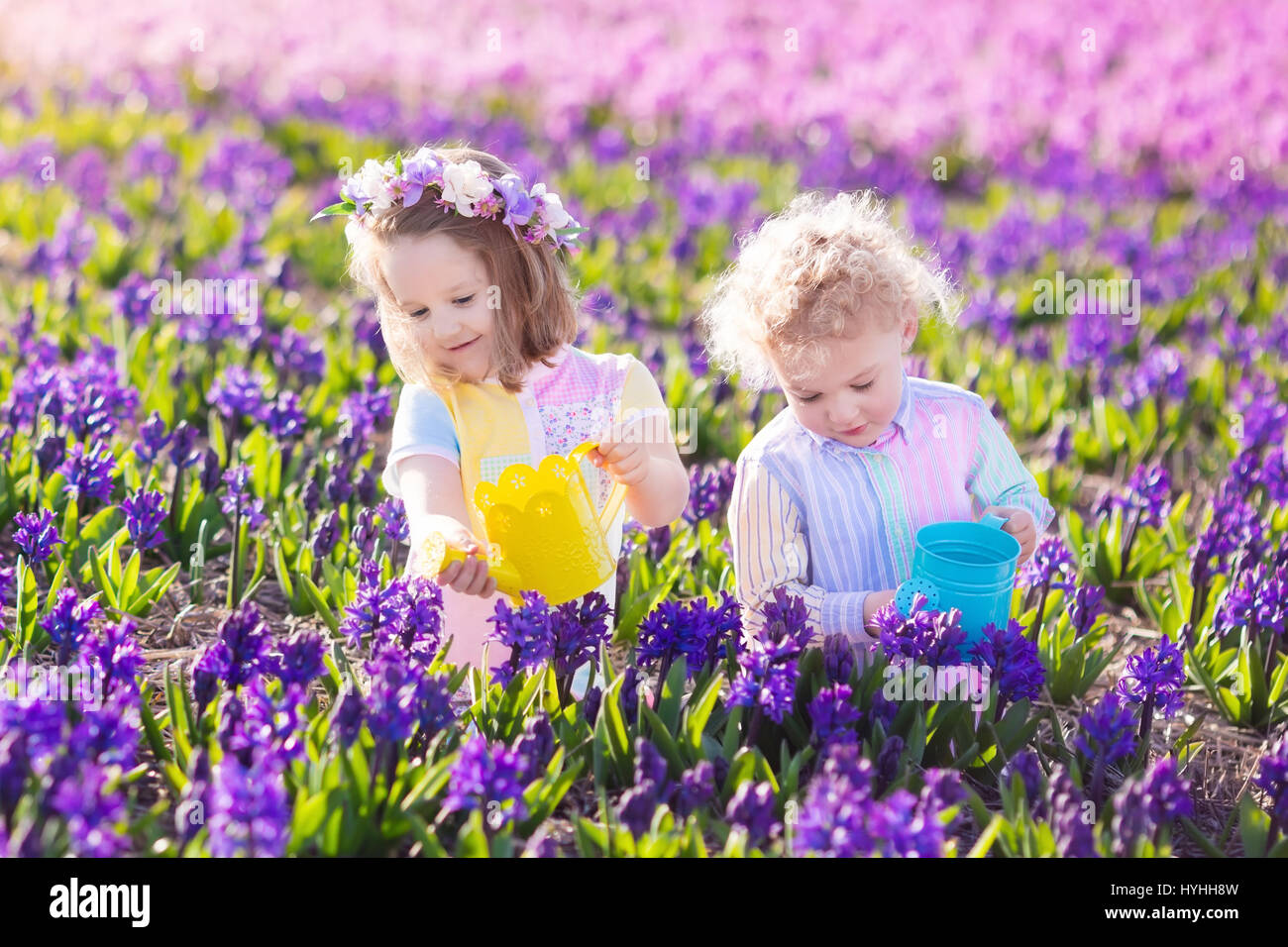 Children planting spring flowers in sunny garden. Little boy and girl ...