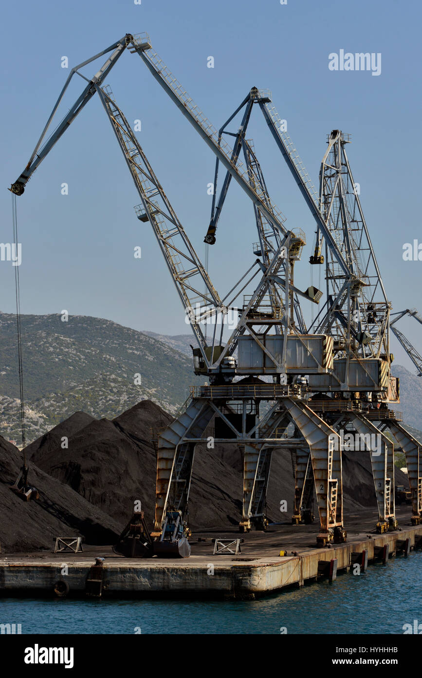 Portrait view of harbour cranes with mounds of coal awaiting to be ...
