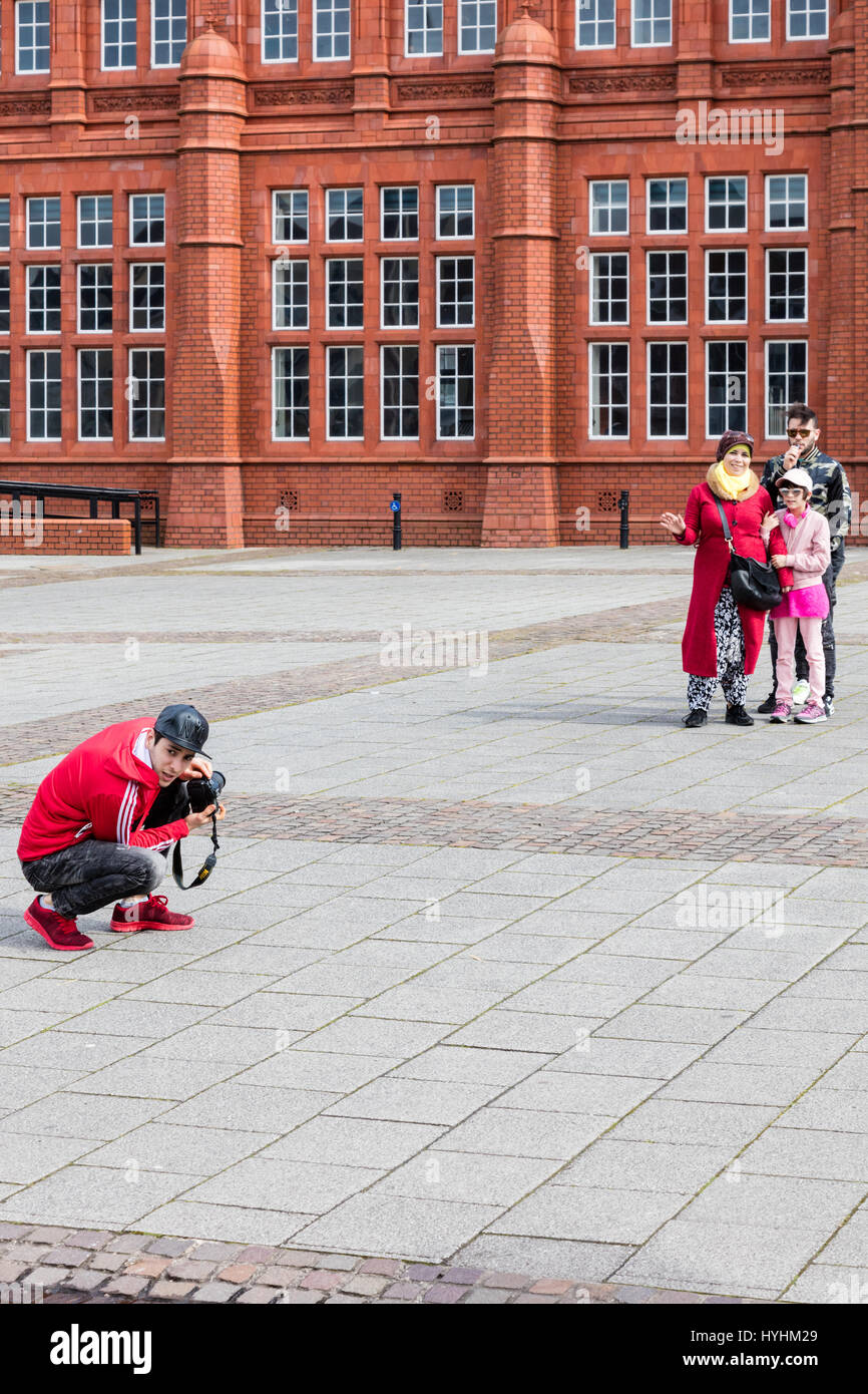A young photographer takes a photo of his family on Cardiff Docks ...