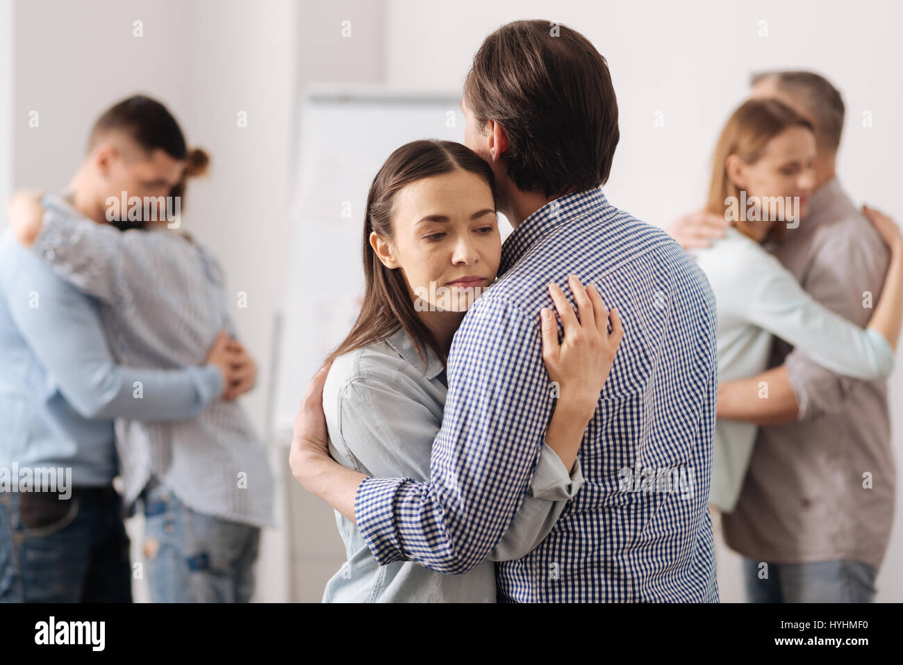 Serious brunette hugging her colleague Stock Photo - Alamy