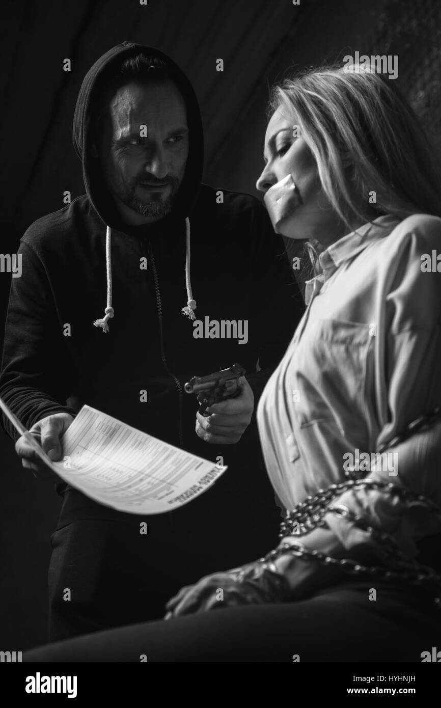 Evil greedy criminal making a hostage sign the papers Stock Photo - Alamy