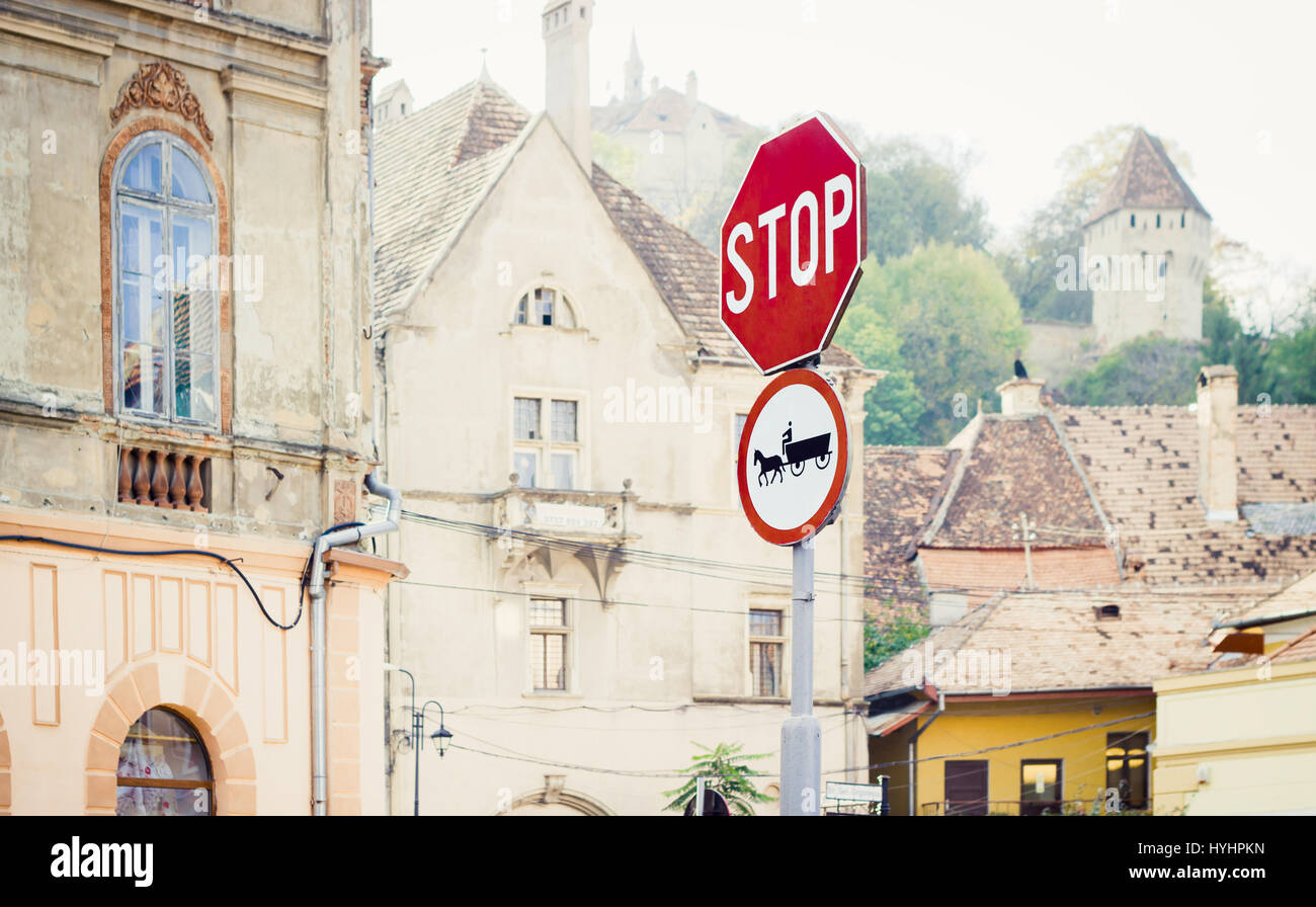 Stop and Horse-drawn vehicles road signs with old town buildings on the ...