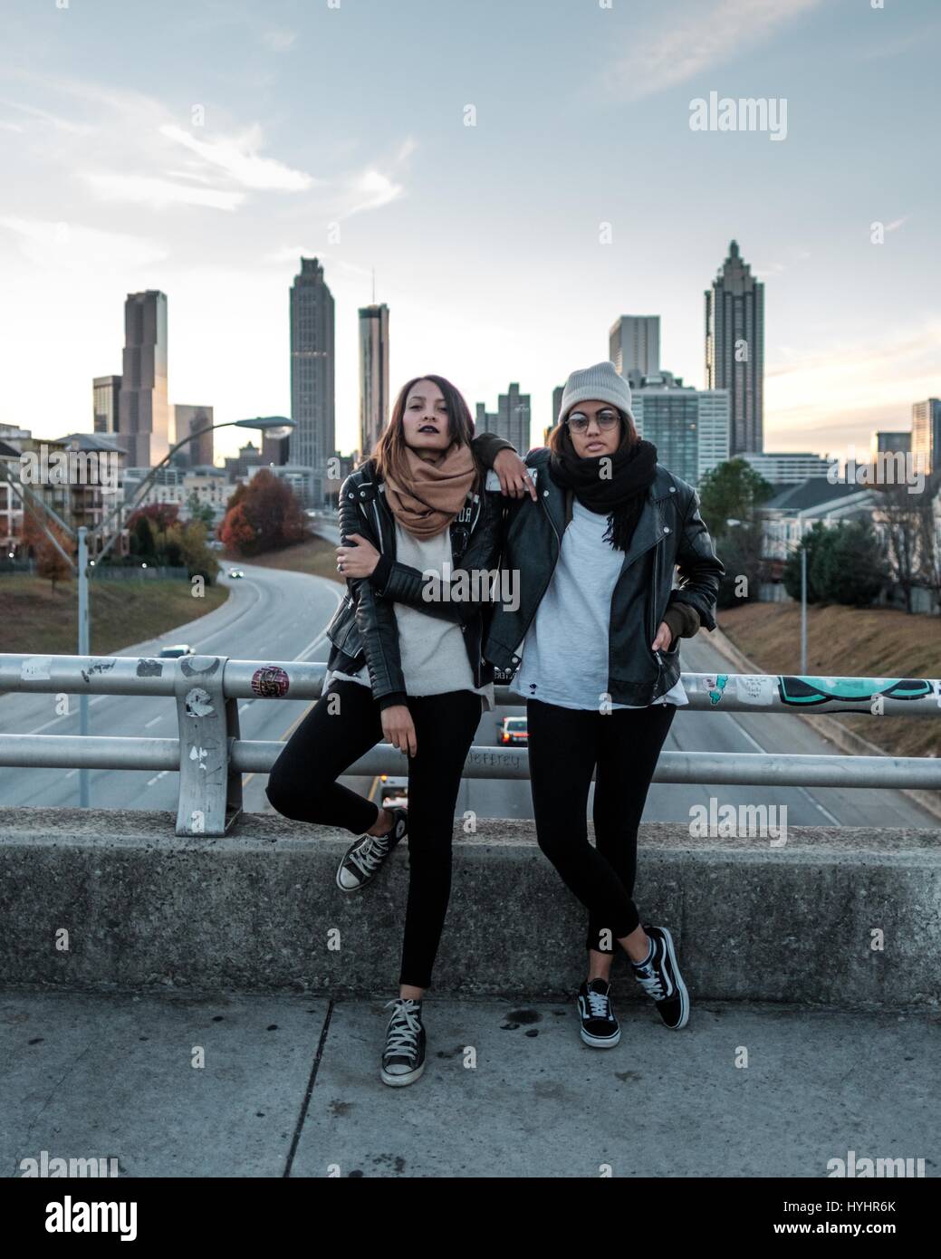 Young ethnic girls standing on bridge with city skyline in the ...