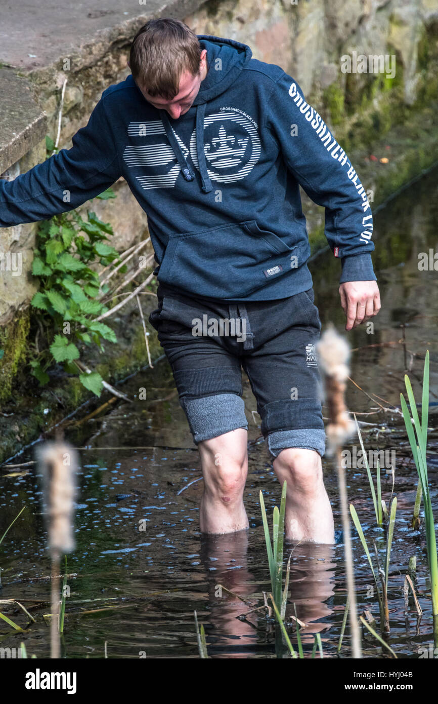 Man with his jeans rolled up wading through a shallow pond Stock Photo ...