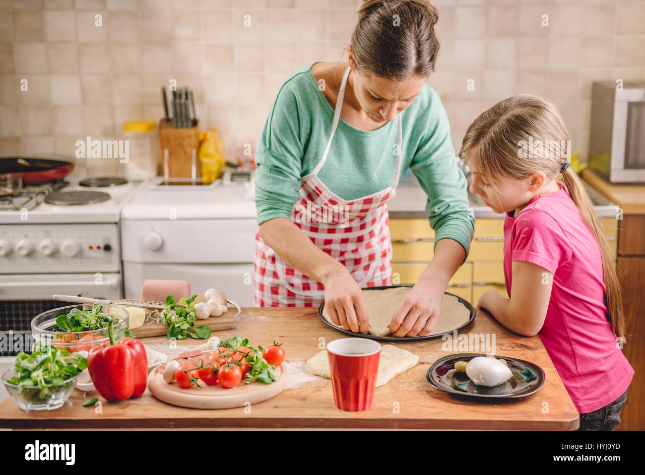 Mother and daughter preparing pizza in the kitchen Stock Photo - Alamy