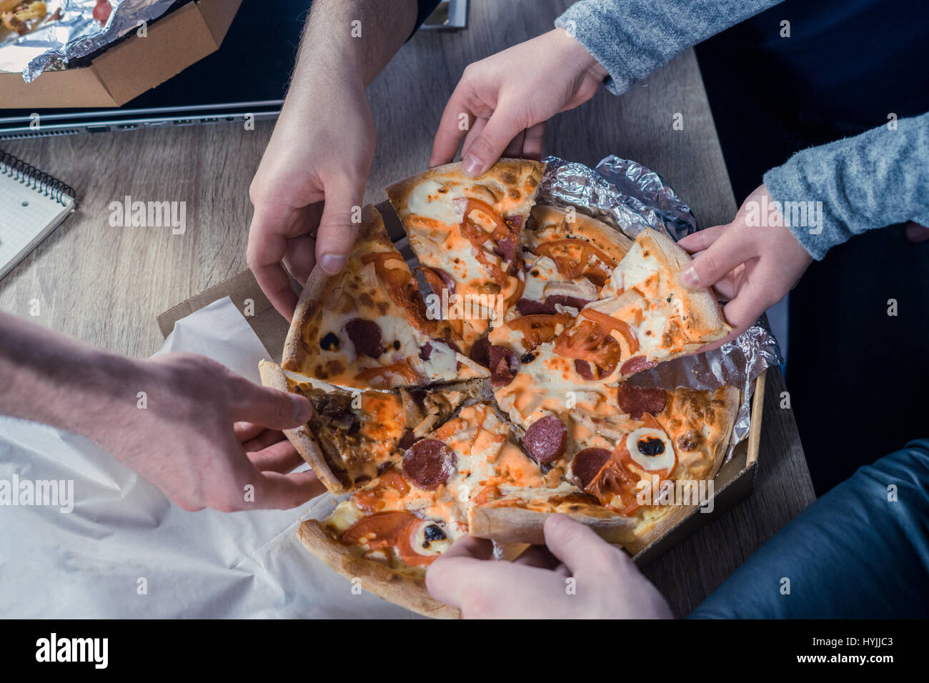 Eating pizza together in office. Top view of hands taking pizza ...