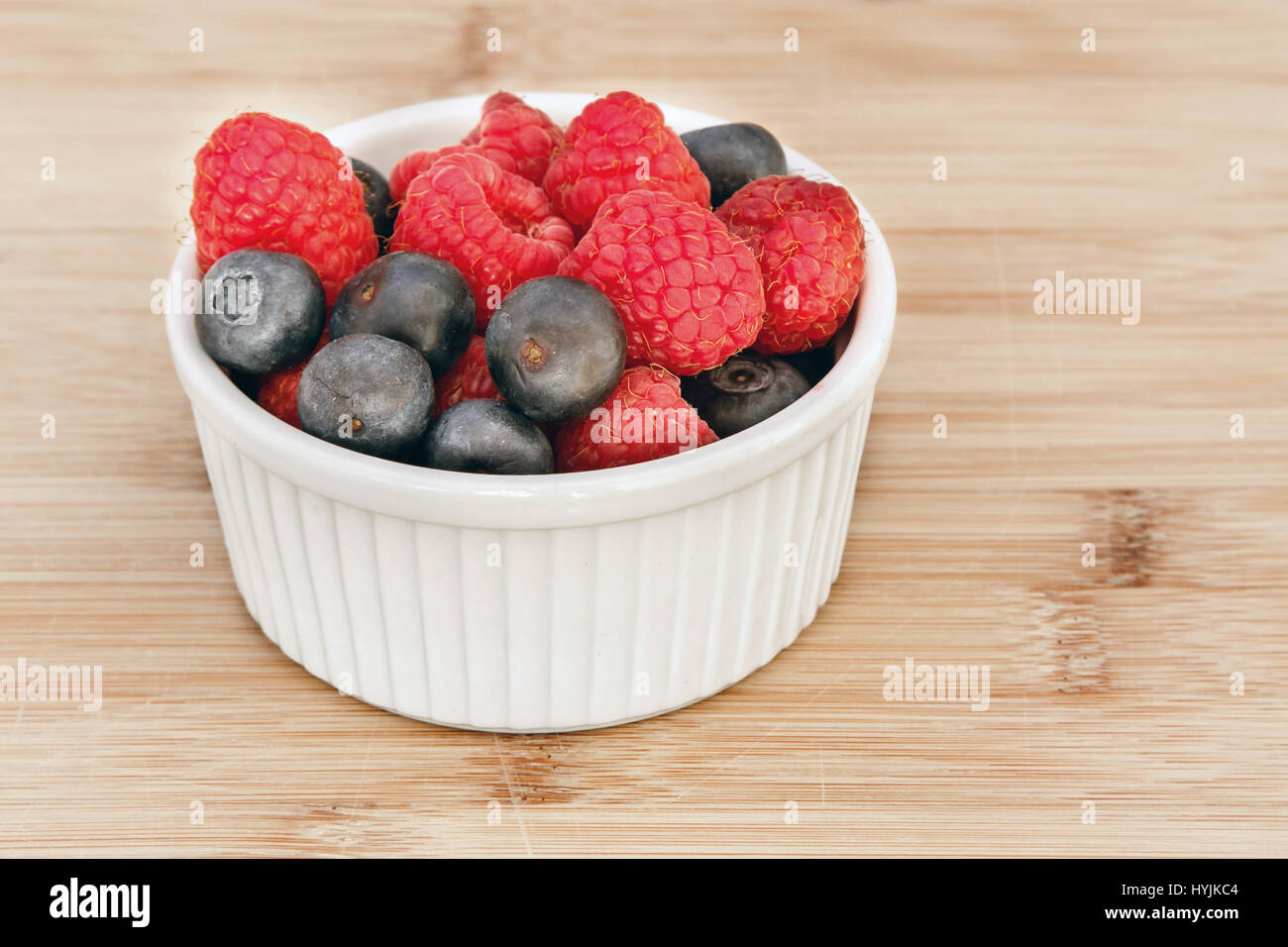 Berry mix of raspberry and blueberry in a white cup Stock Photo - Alamy